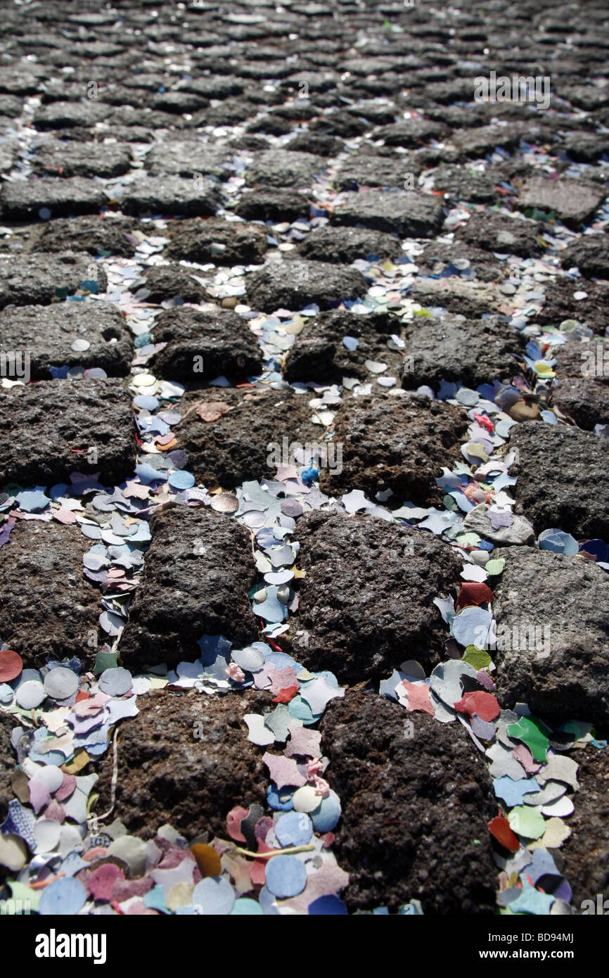 lots of colourful confetti and garlands on paved street road in sun ...