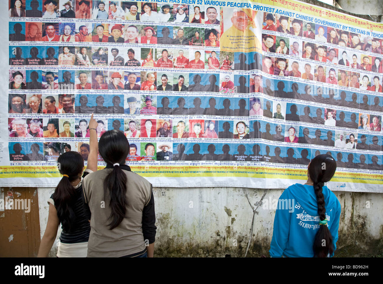 Tibetan women looking a poster showing Tibetans executed or imprisoned ...