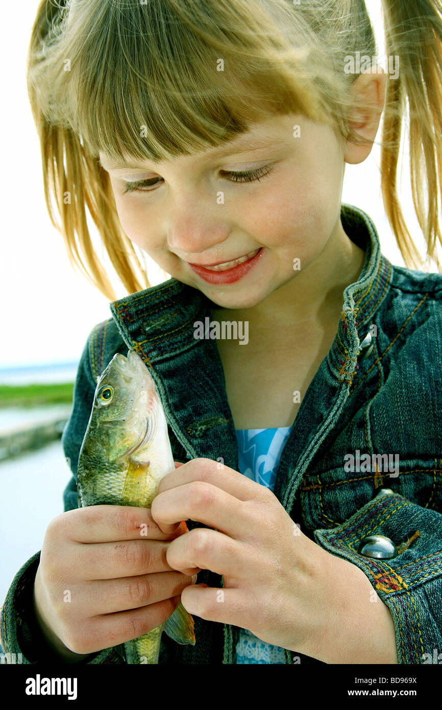 Little girl holding a fish and smiling Stock Photo - Alamy