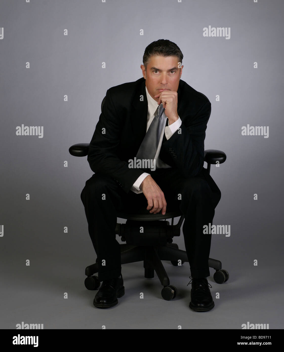 A business executive looks seriously directly at camera from business ...