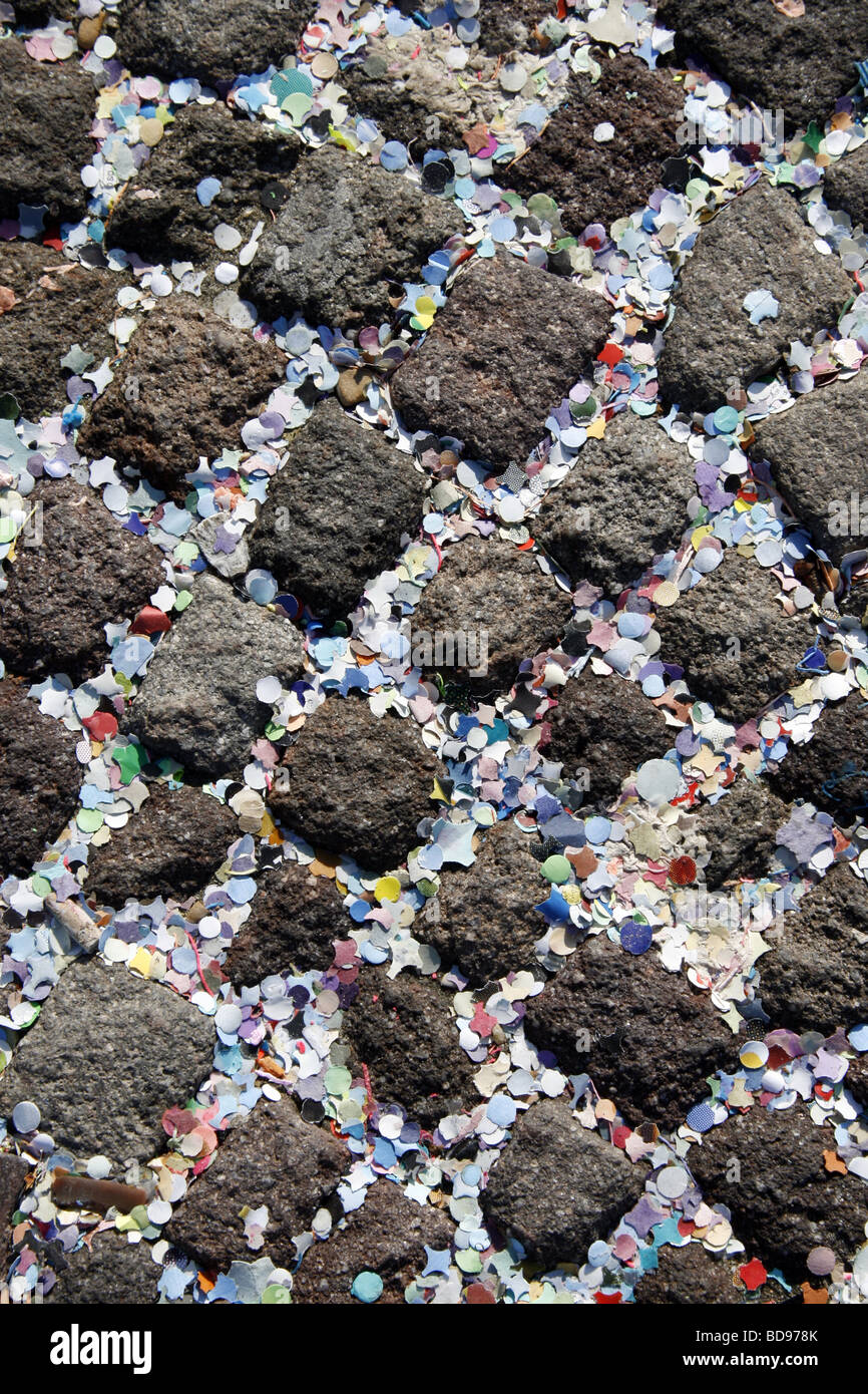 lots of colourful confetti and garlands on paved street road in sun ...