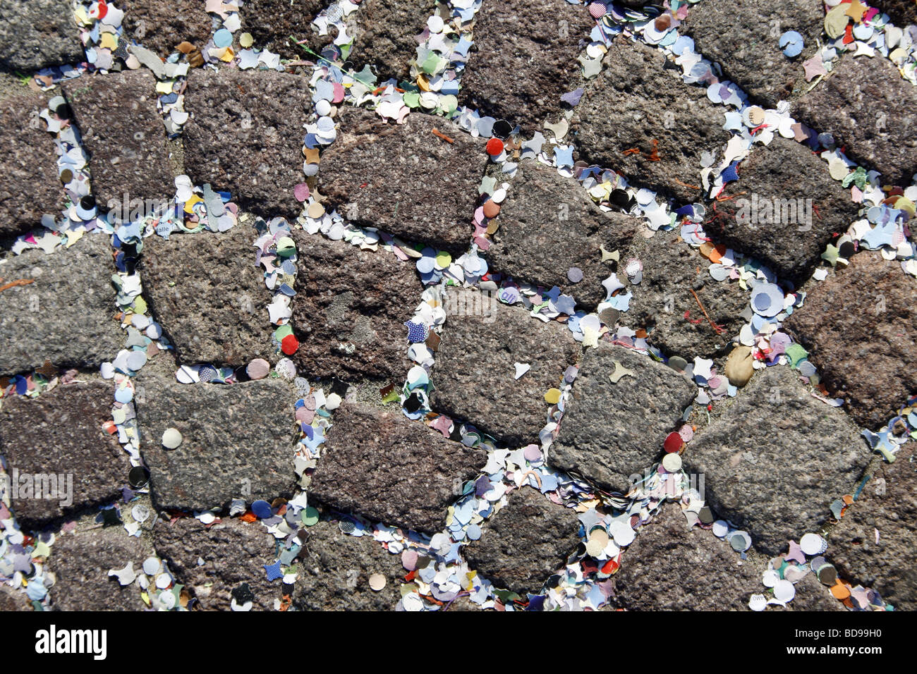 lots of colourful confetti and garlands on paved street road in sun ...