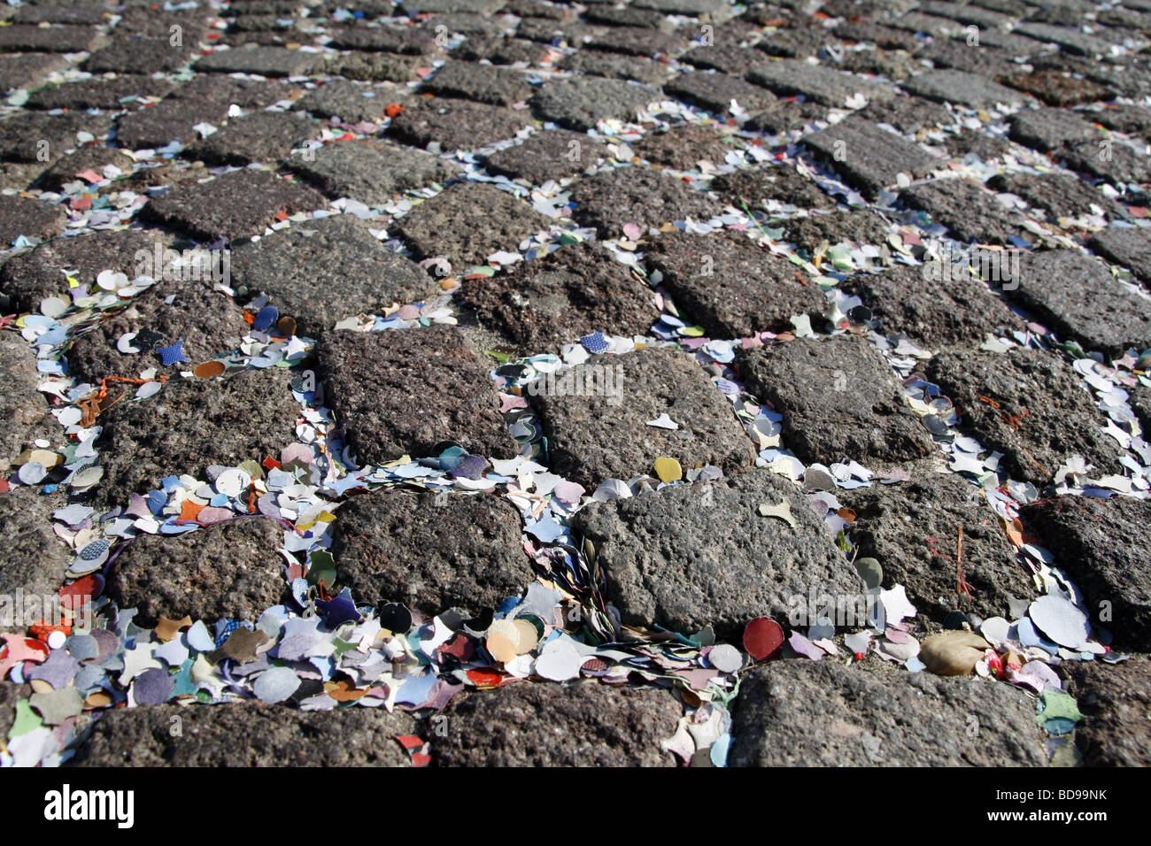 lots of colourful confetti and garlands on paved street road in sun ...