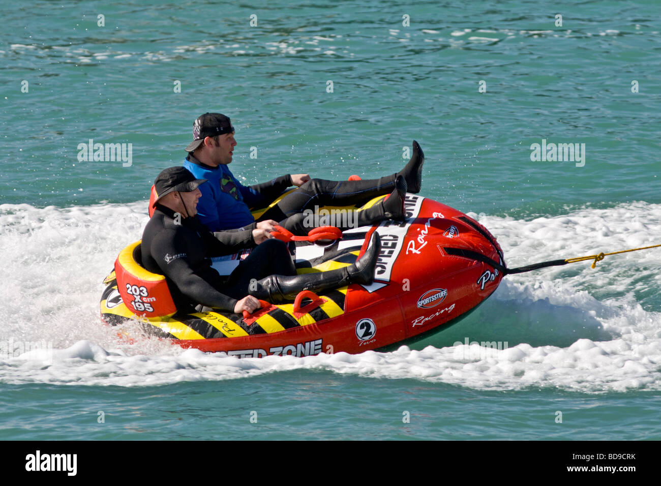 Two Adventurous Men Being Towed In A Rubber Craft Behind A Speeding