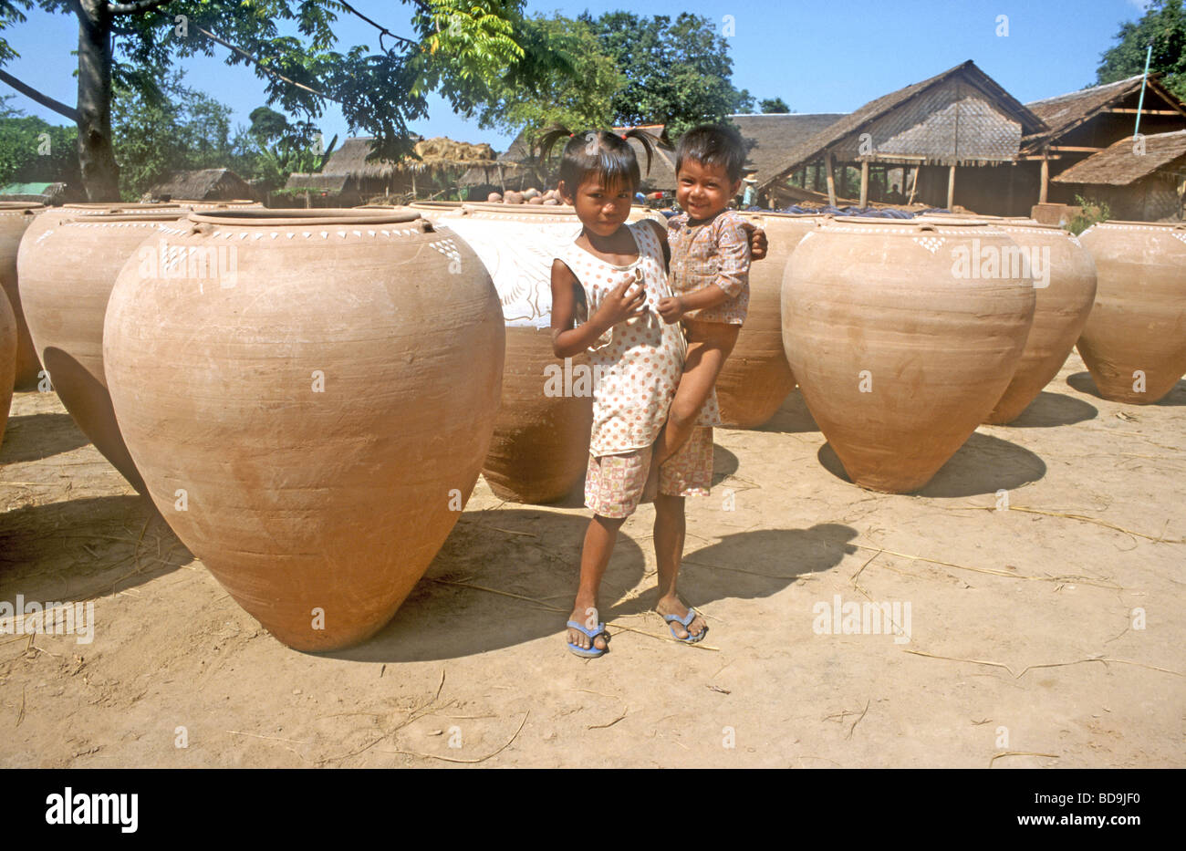 Burmese children standing among huge pots traditionally made at Twante ...
