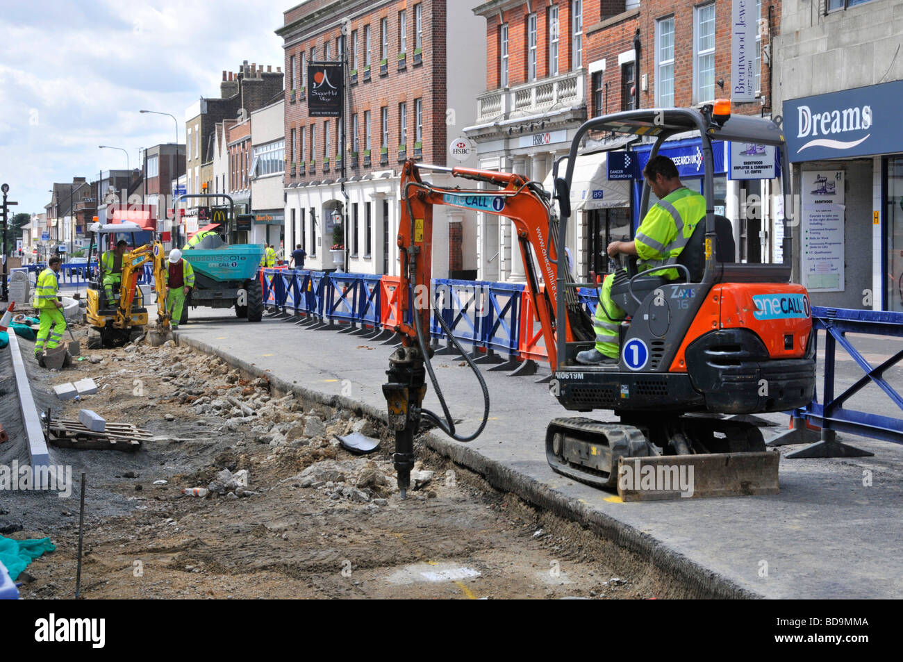 Scene in Brentwood shopping high street workmen & road works machine ...