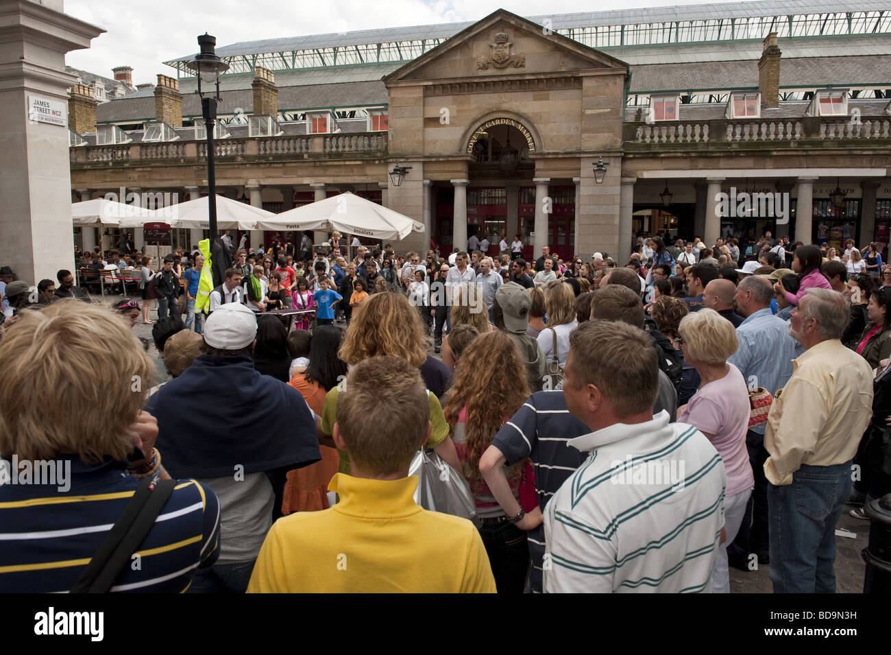 Crowds of tourists and visitors watching street performers/buskers in a ...