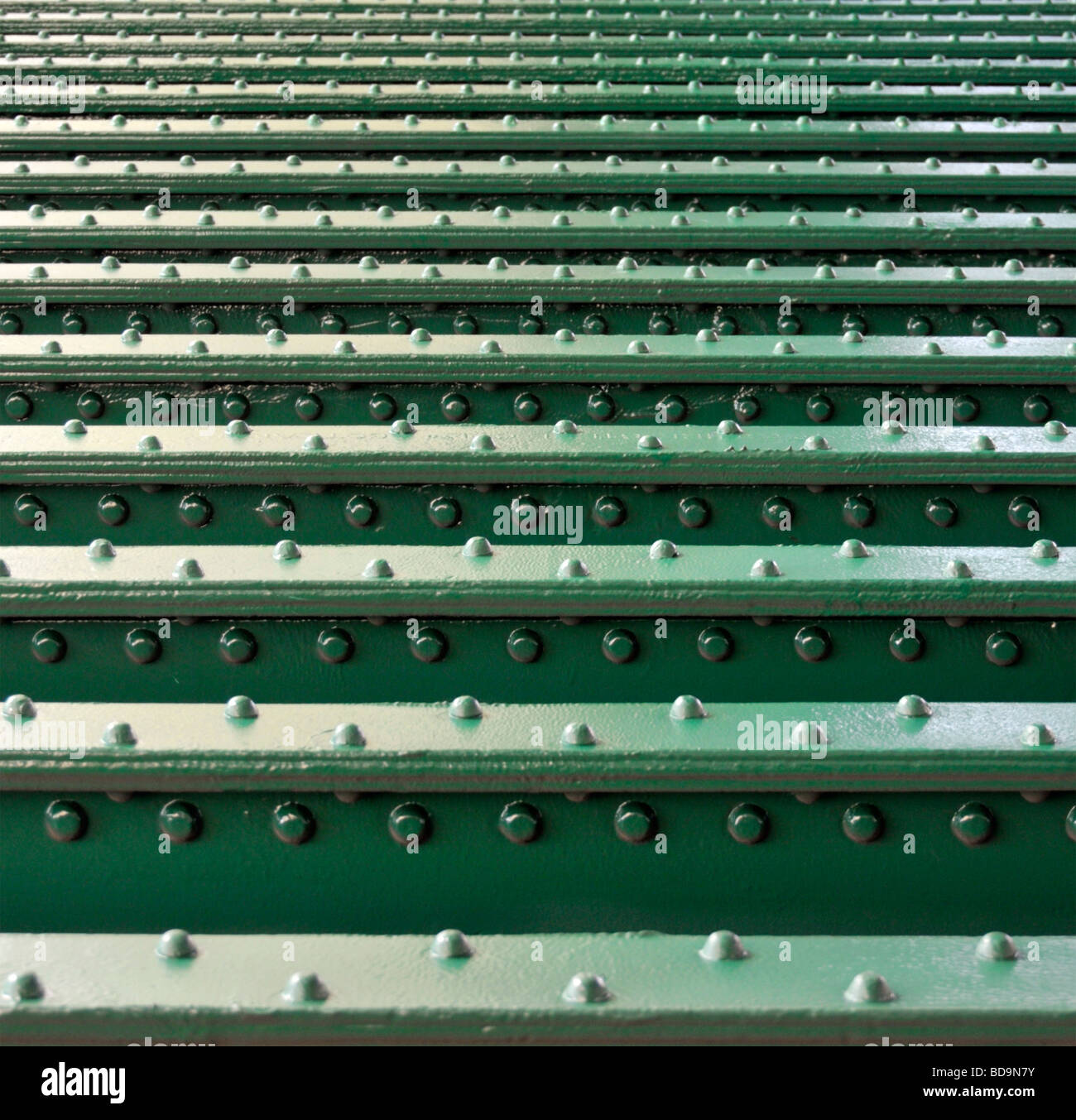 Rows of receding lines of rivets in steel girders on underside of ...