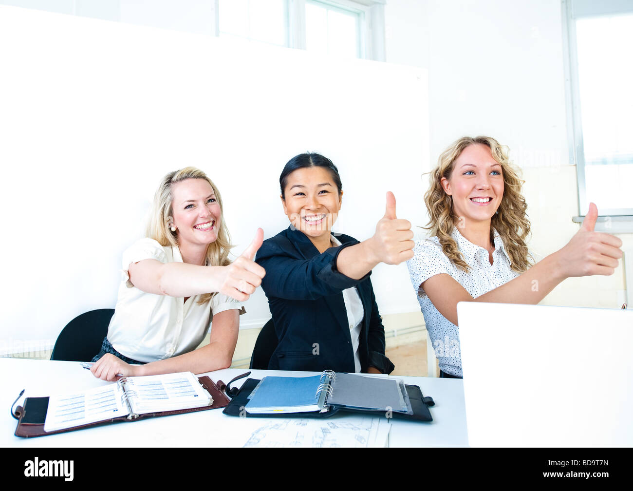 Group of business women at the office working giving boss thumbs up ...