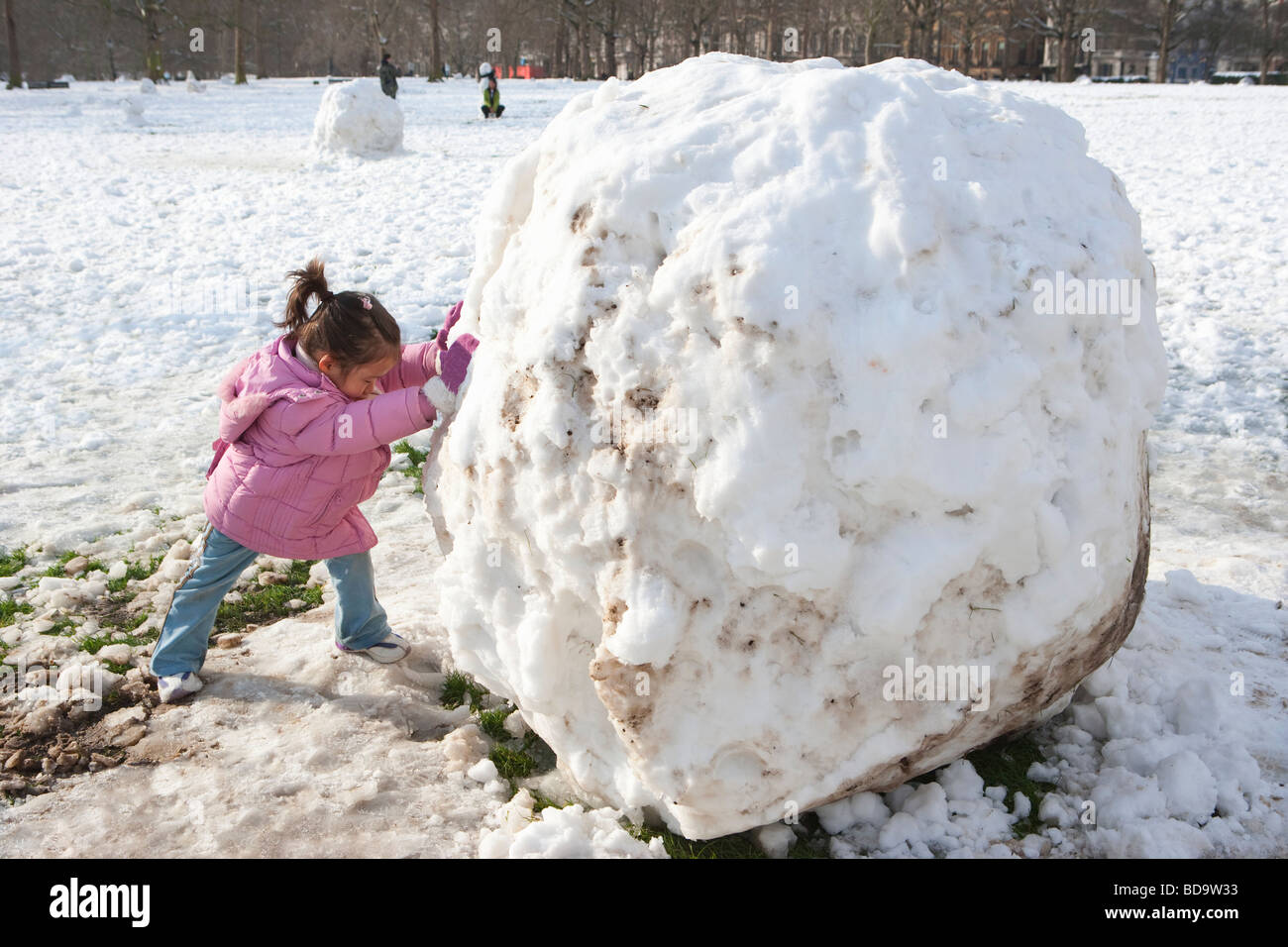 Toddler trying to push huge snowball Green Park London England Stock ...