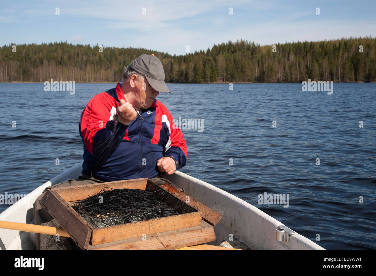 Elderly man checking baited hook line in a small rowboat / skiff ...