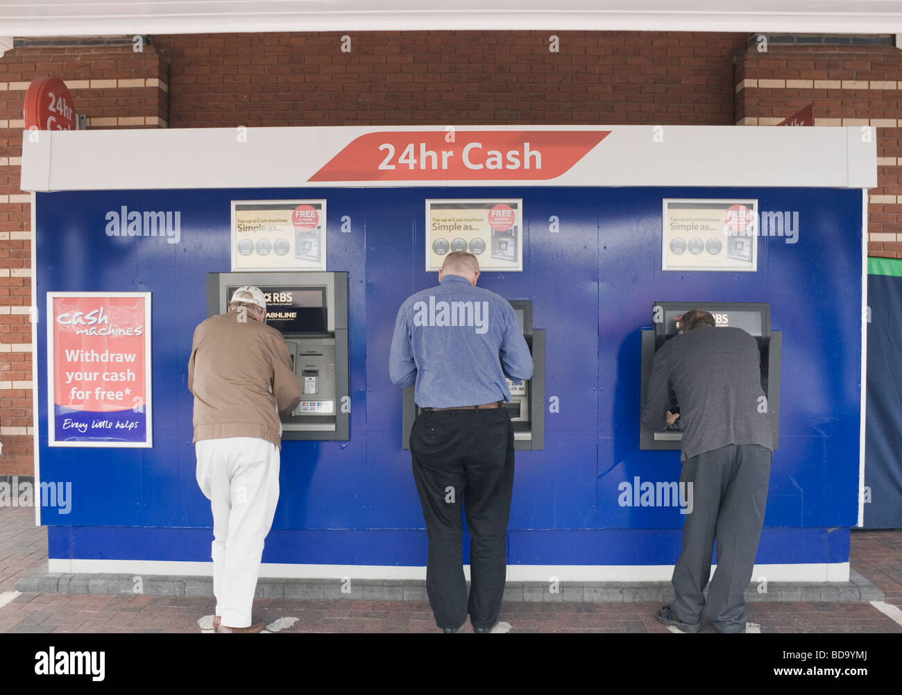 Three men withdrawing money at twenty four hour cash machine Stock ...