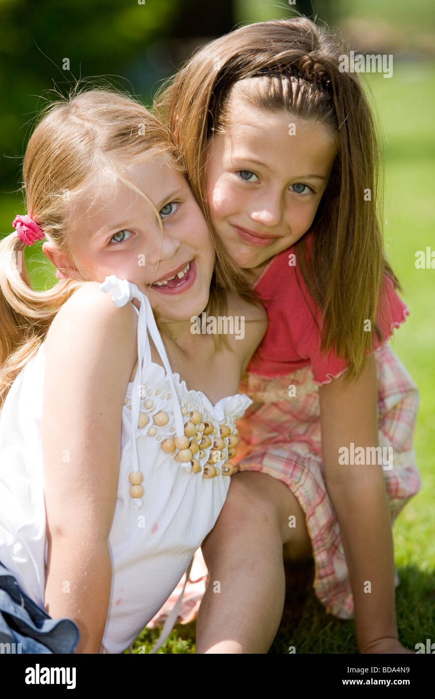 Two young girls posing together outdoors on a sunny day Stock Photo - Alamy