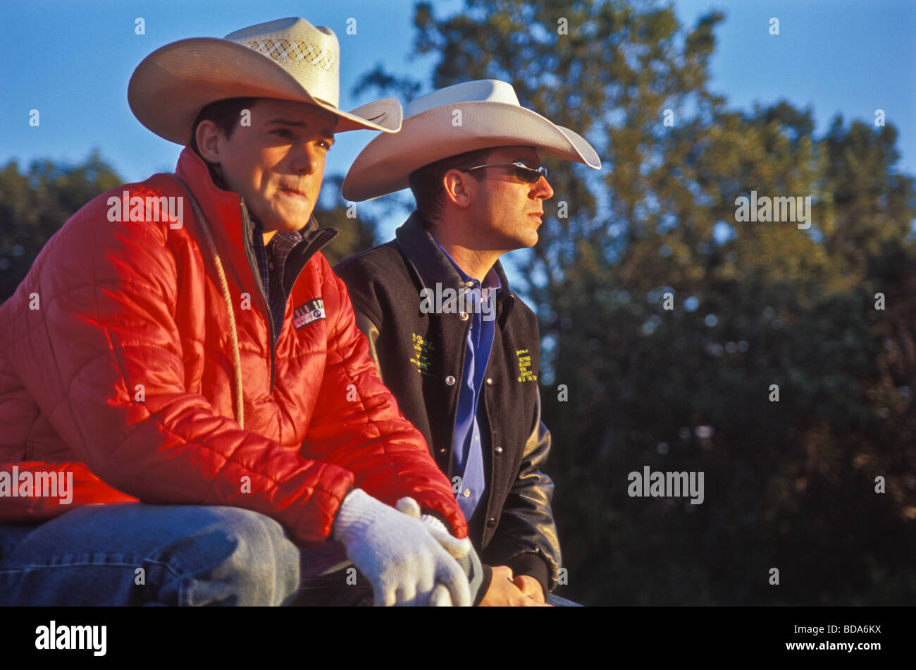 Two cowboys sit on fence overlooking rodeo arena Stock Photo - Alamy