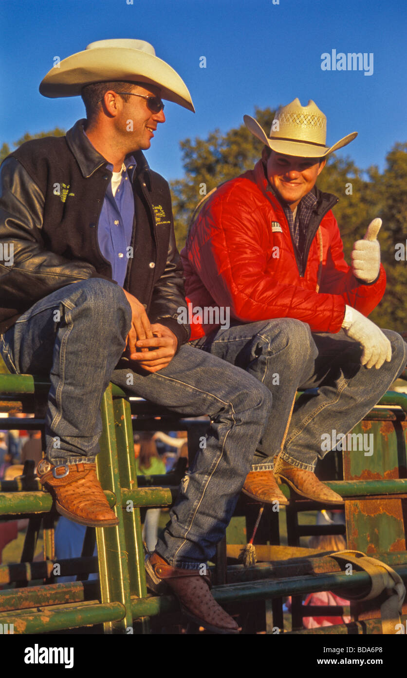 Two cowboys sit on fence overlooking rodeo arena Stock Photo - Alamy