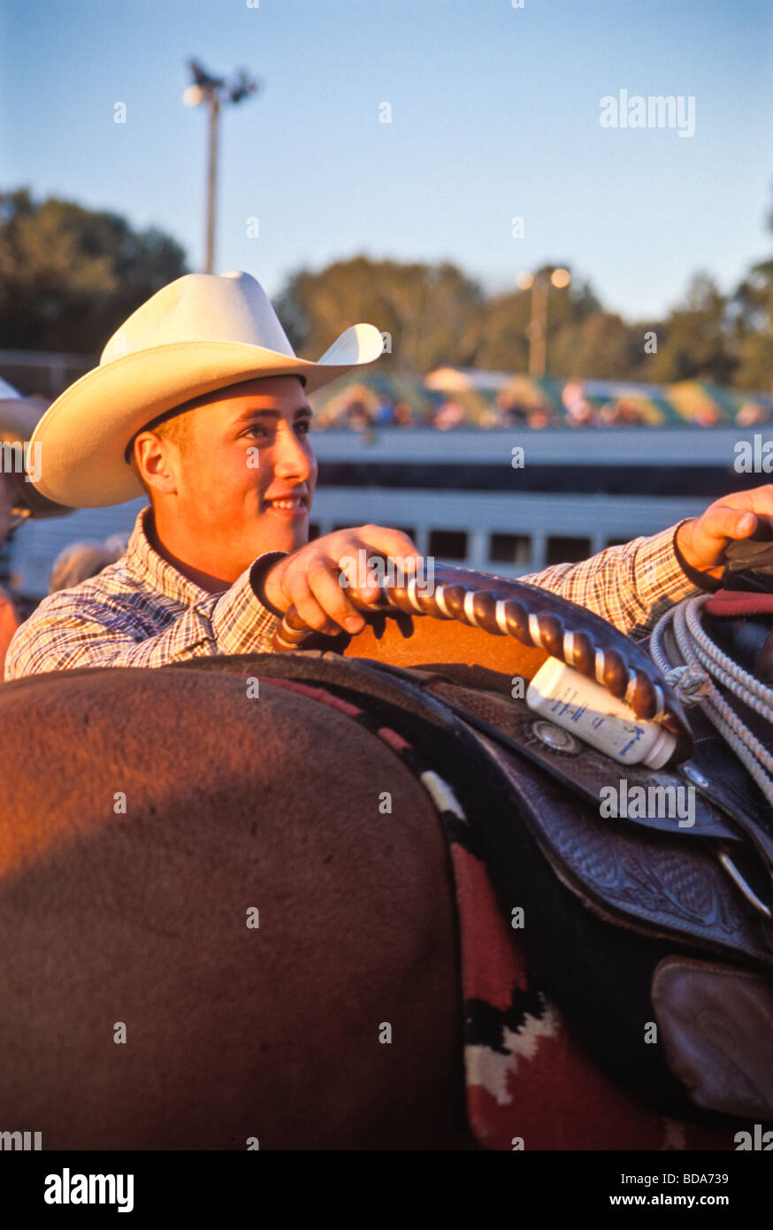 Smiling cowboy saddles up at county fair rodeo Stock Photo - Alamy