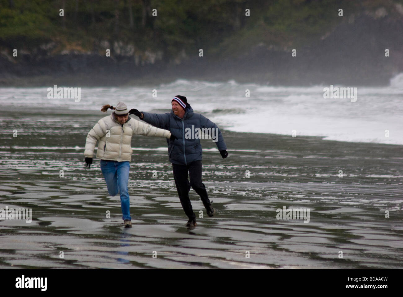 Couple playing on the beach, man chasing woman with ponytail, near ...