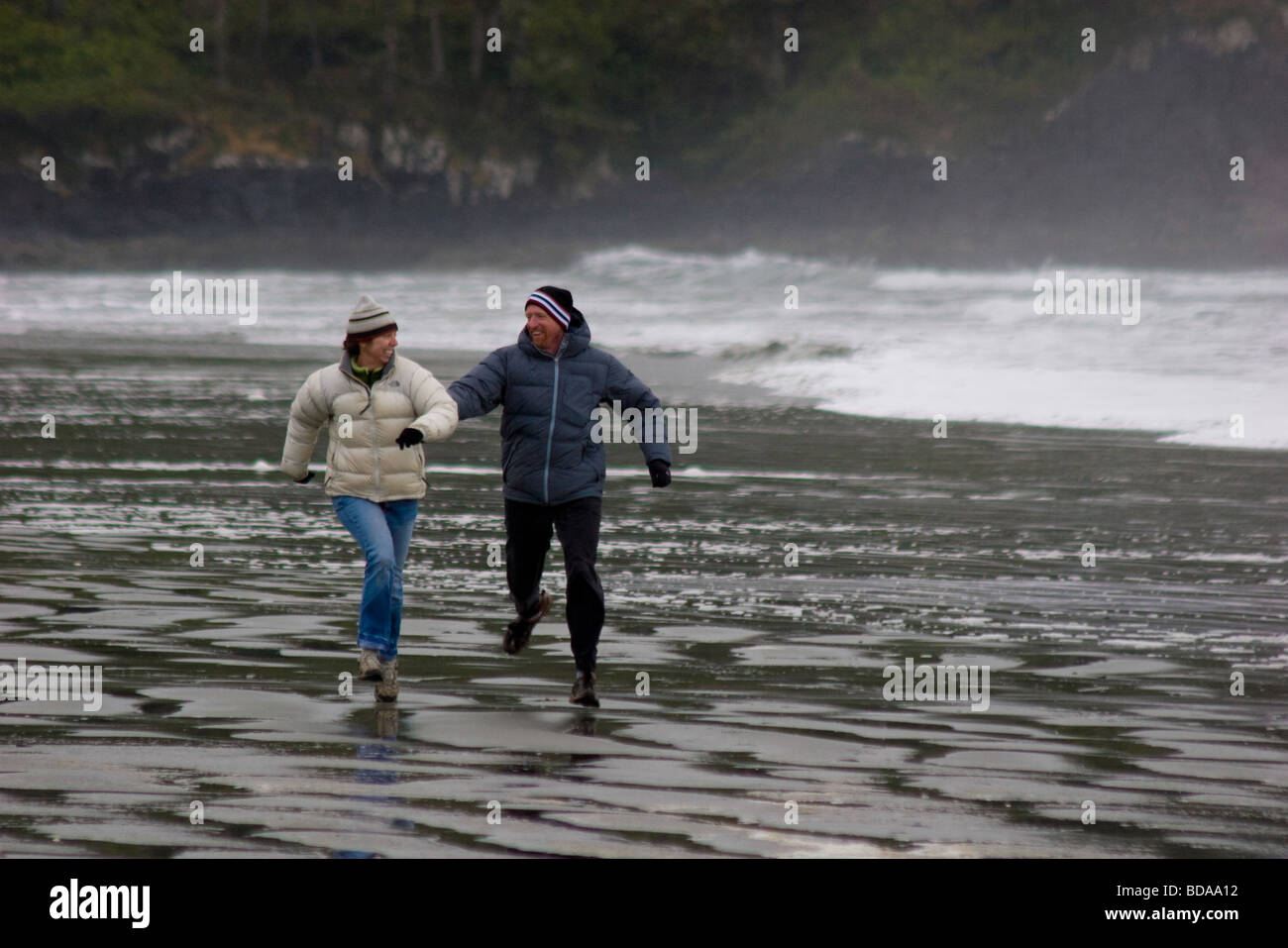 Couple playing on the beach, man chasing woman, near Tofino, BC Stock ...