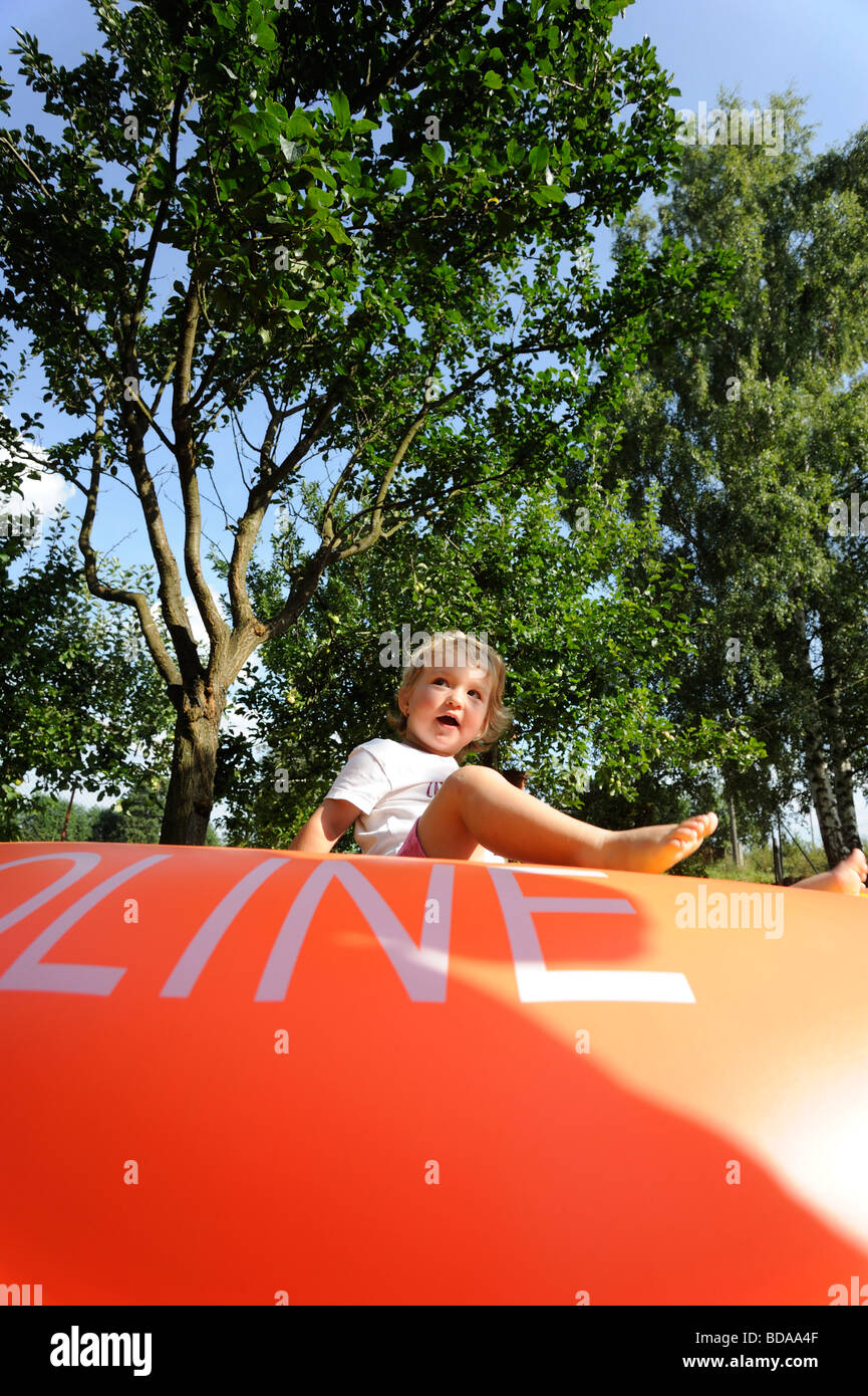 Blond Child girl Jumping on orange Trampoline in Yard Stock Photo - Alamy