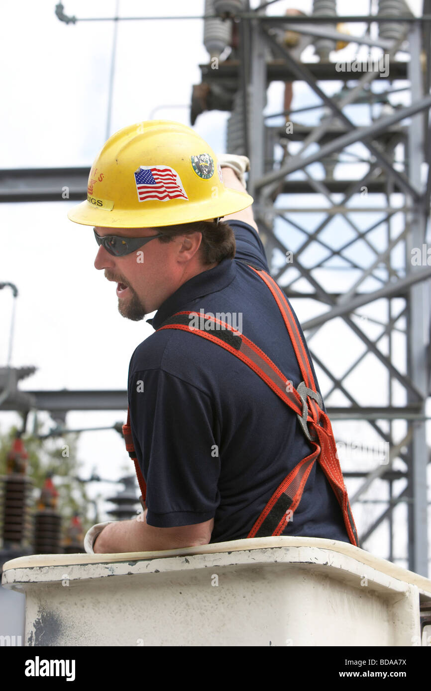 Utility workman wearing safety harness and hardhat climbing an ...