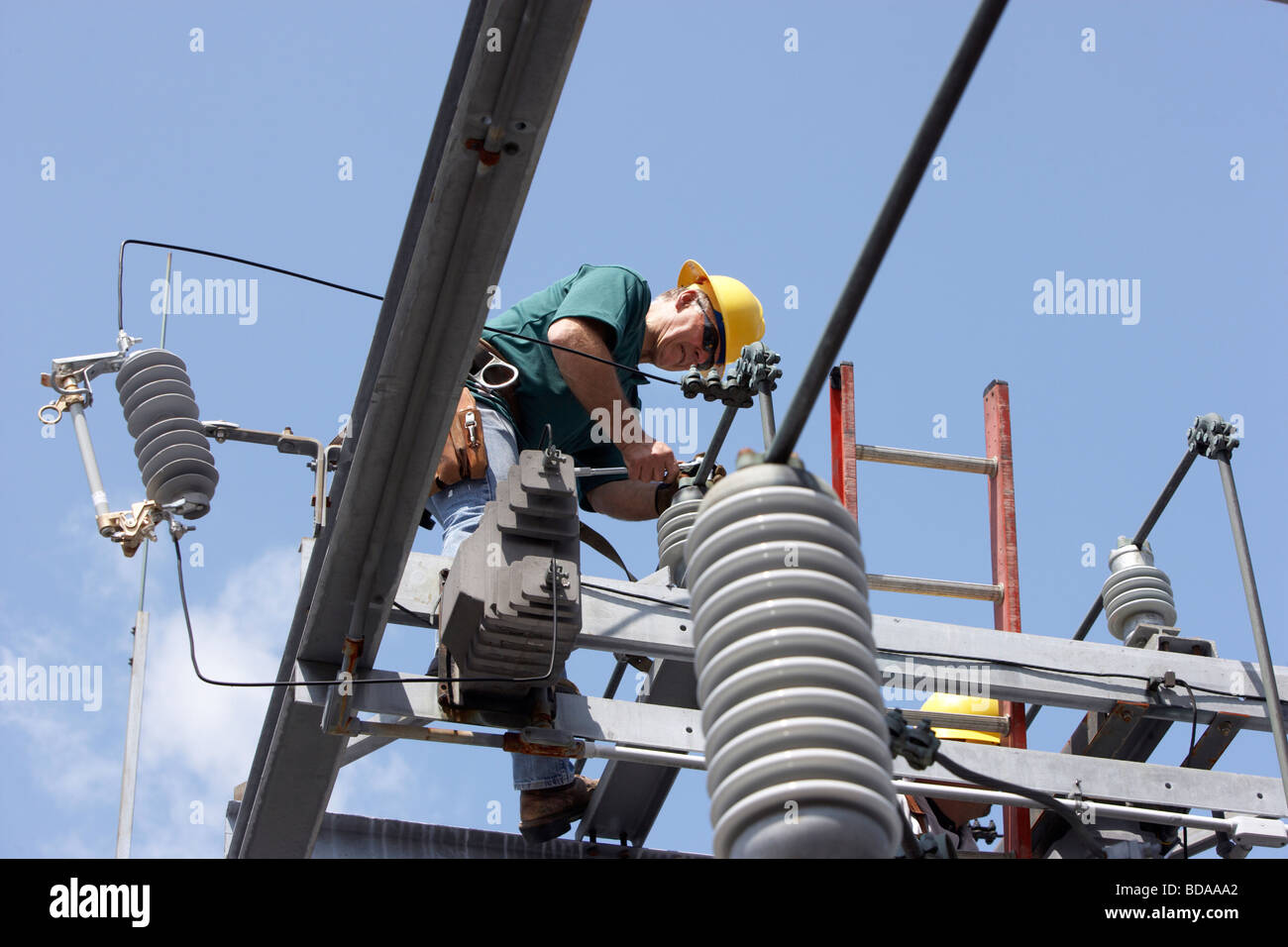 Utility workman wearing safety harness and hardhat installing new ...