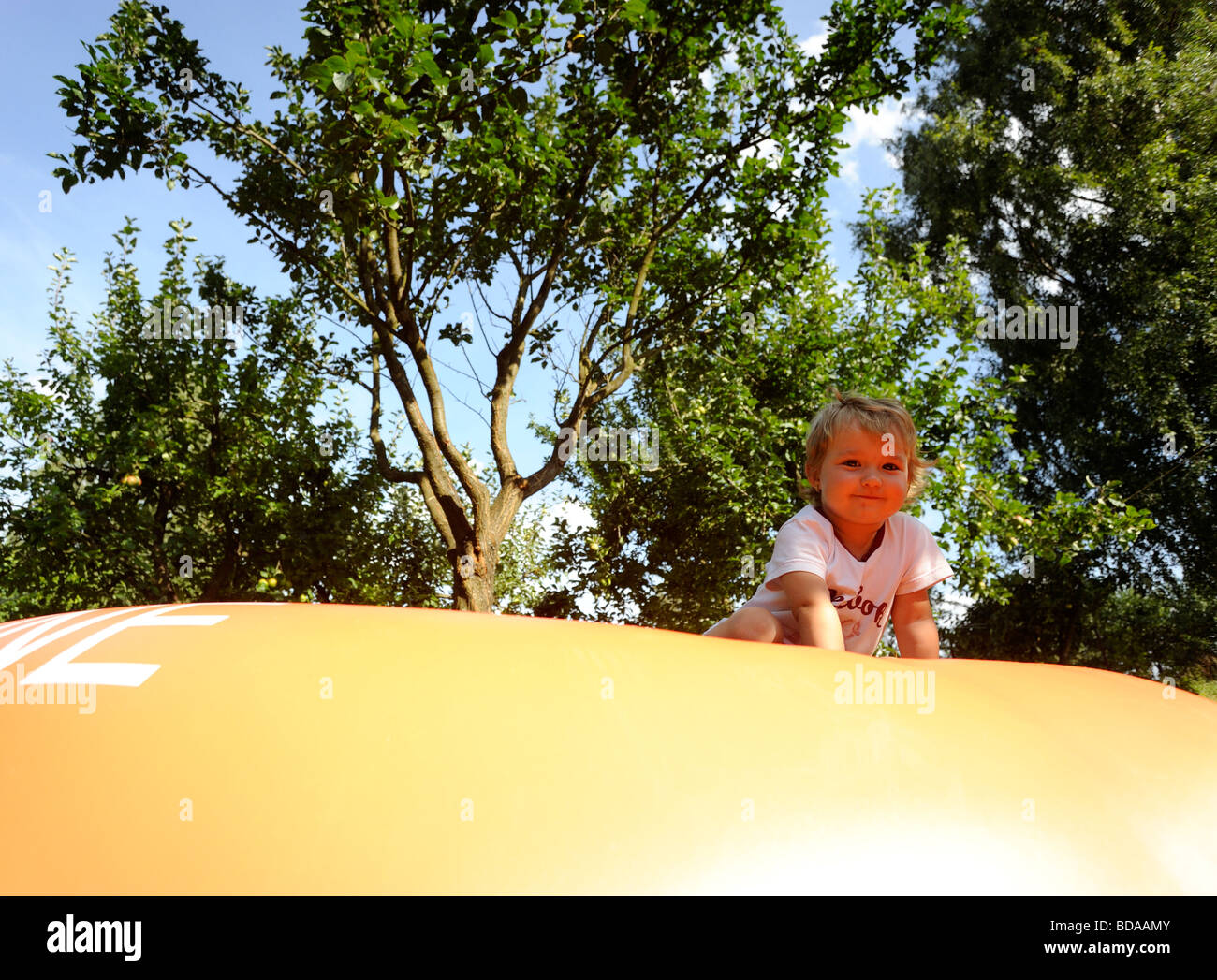 Blond Child girl Jumping on orange Trampoline in Yard Stock Photo - Alamy