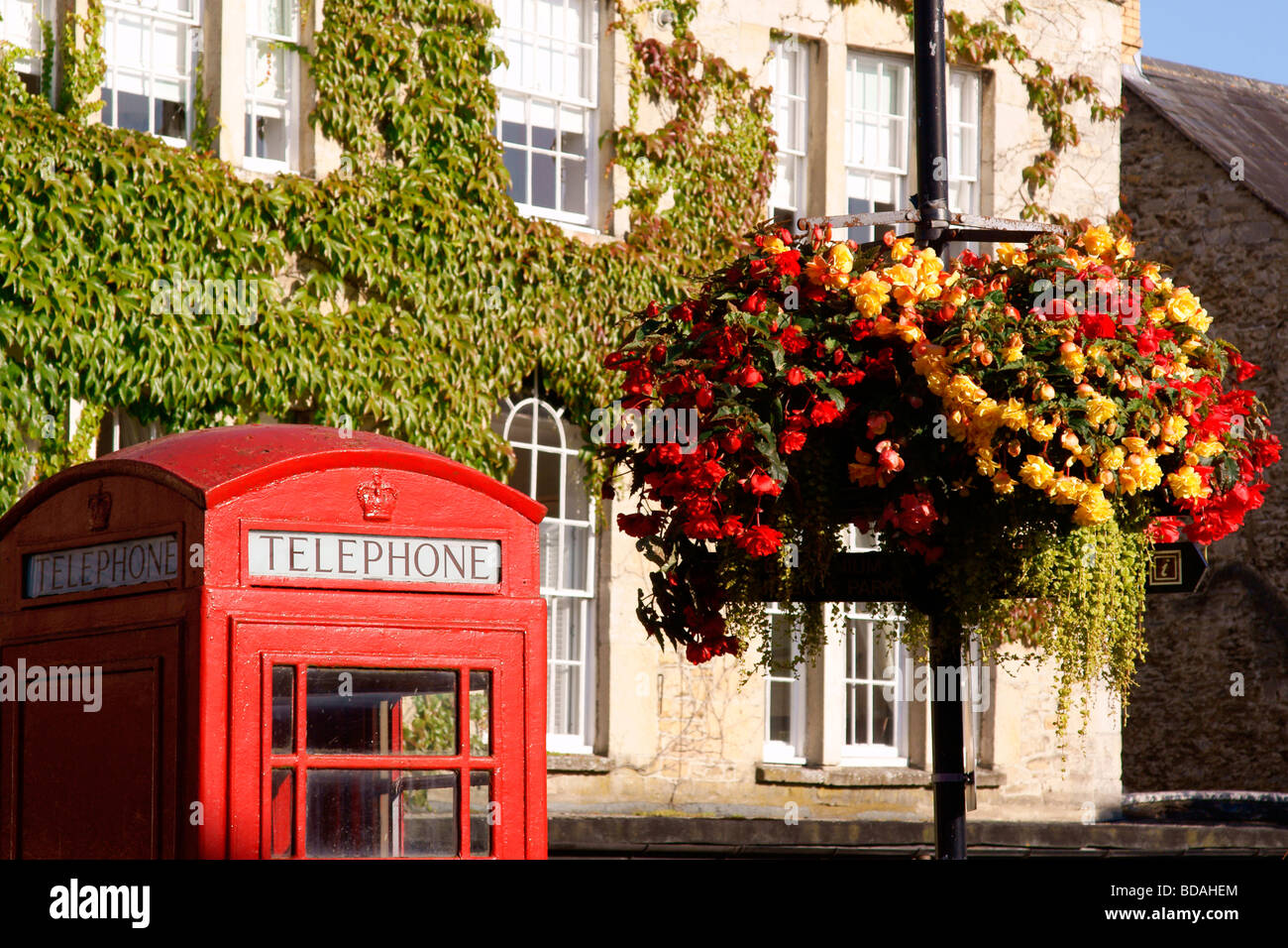 Telephone box with hanging flower basket in Tetbury Stock Photo - Alamy