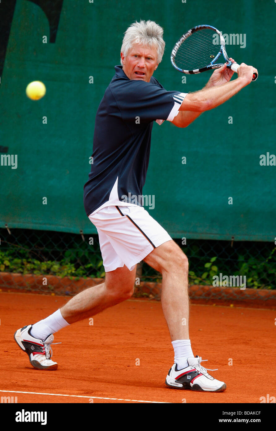 Middleaged man playing a backhand at a tennis tournament Stock Photo ...