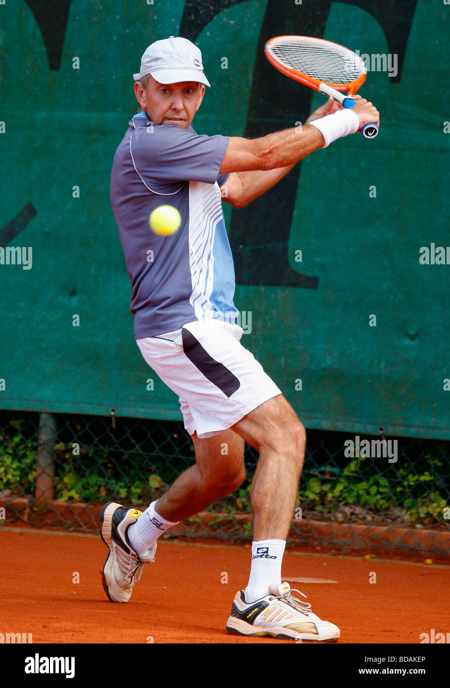 Elderly man playing a backhand at a tennis tournament Stock Photo - Alamy