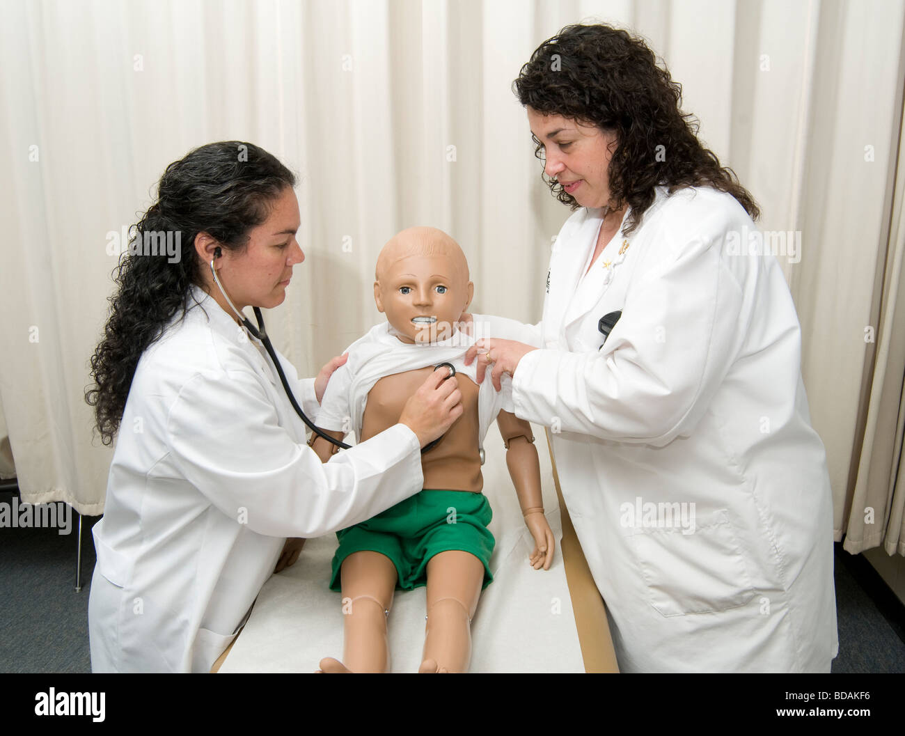 Two female doctors practicing checking the vitals on a dummy child ...