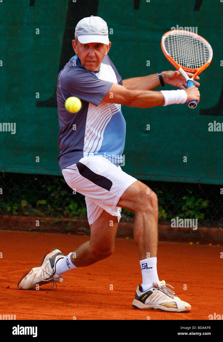 Elderly man playing a backhand at a tennis tournament Stock Photo - Alamy
