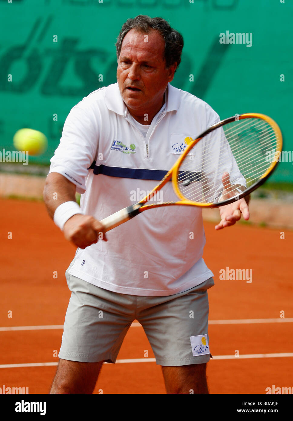Elderly man playing a backhand at a tennis tournament Stock Photo - Alamy