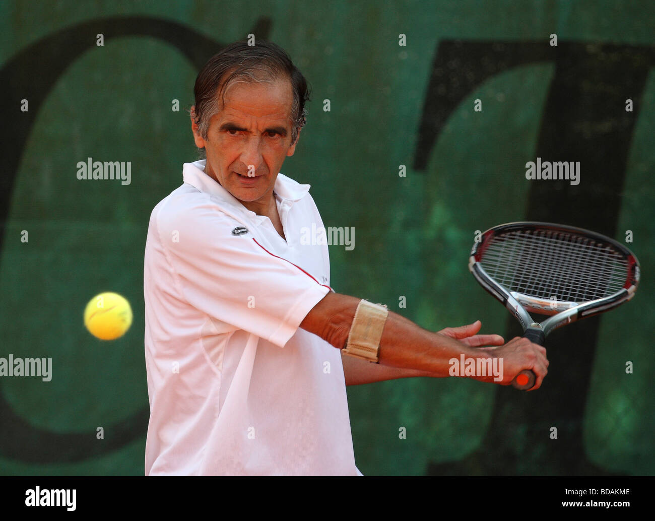 Elderly man playing a backhand at a tennis tournament Stock Photo - Alamy