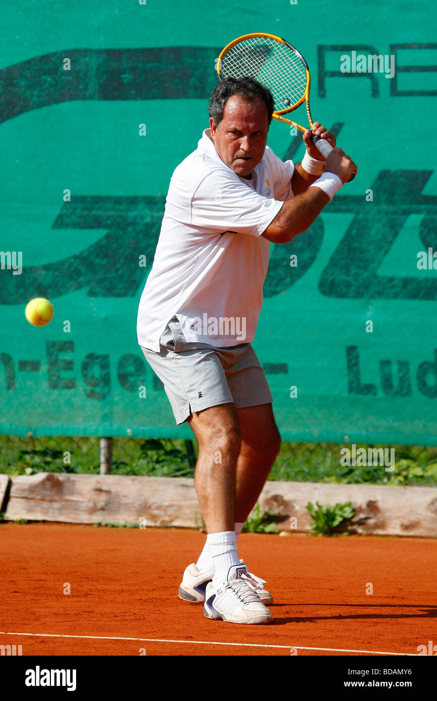 Elderly man playing a backhand at a tennis tournament Stock Photo - Alamy