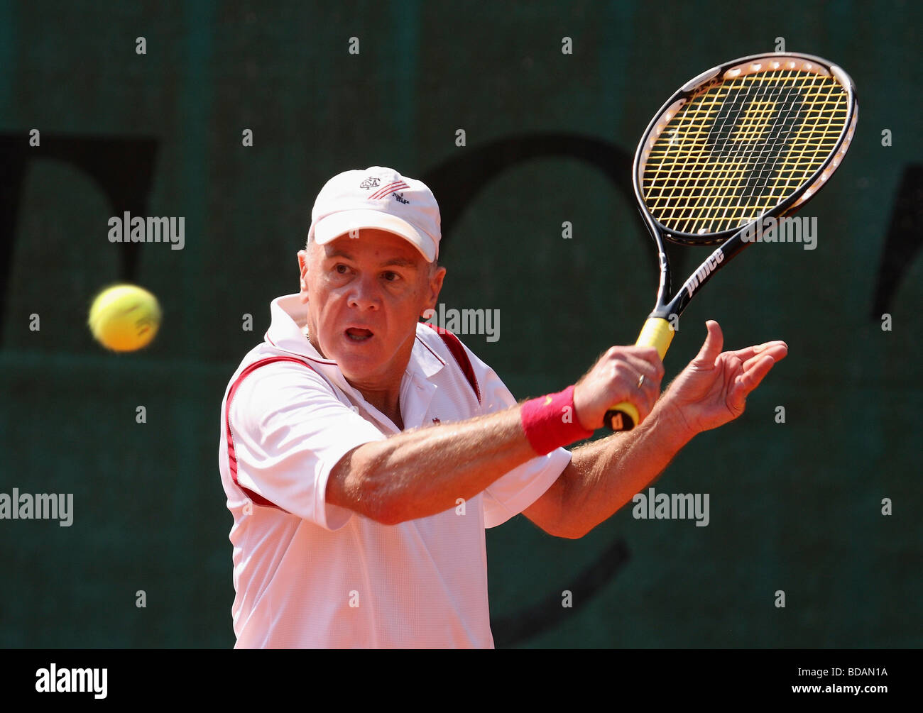 Elderly man playing a backhand at a tennis tournament Stock Photo - Alamy
