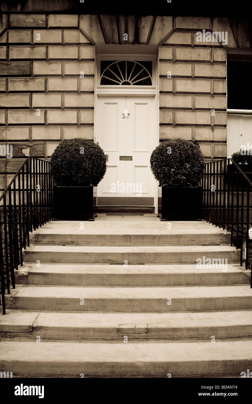 Stone steps lead up to a white door of an expensive townhouse in ...