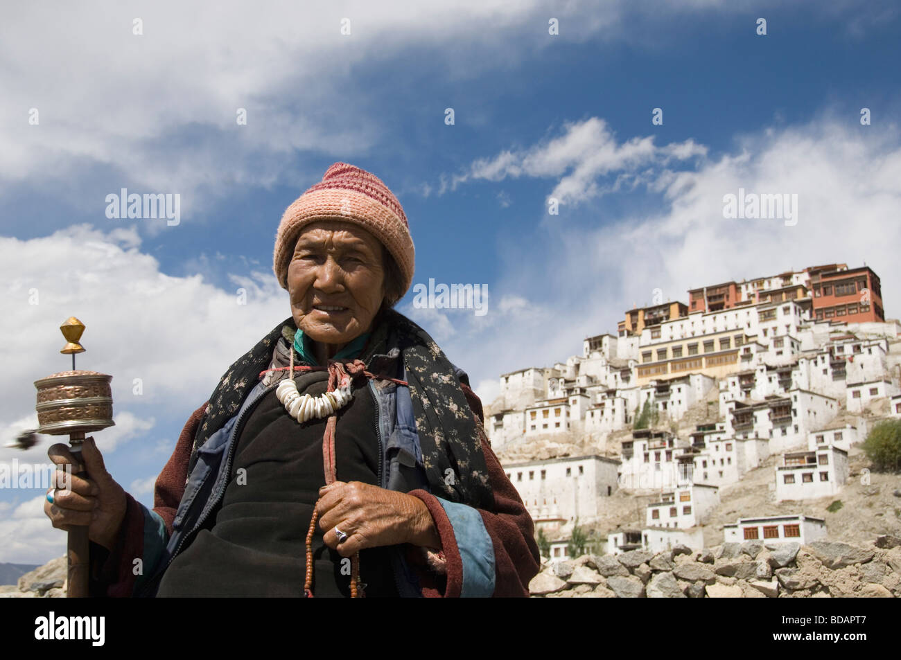 Woman praying with monastery in the background, Thiksey Monastery ...