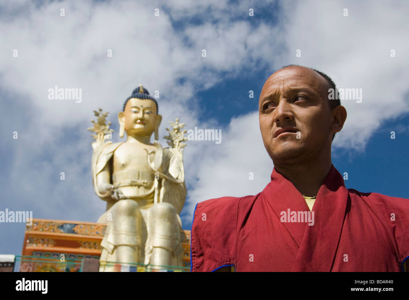 Monk standing in front of a statue of Buddha in a monastery, Likir ...