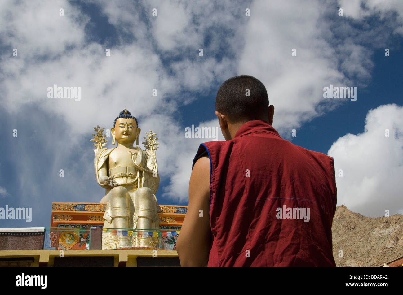 Monk standing in front of a statue of Buddha in a monastery, Likir ...