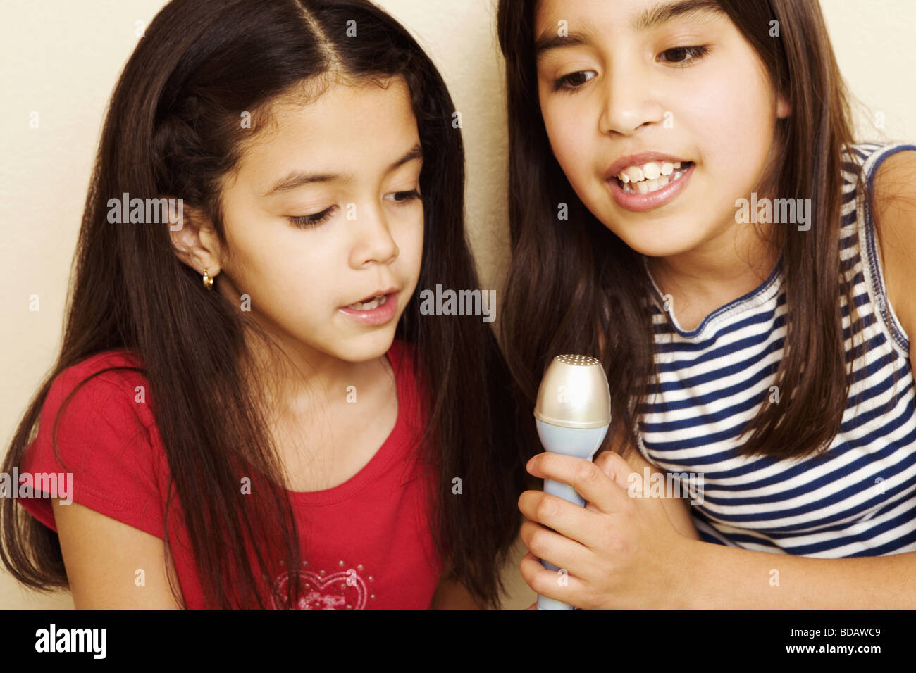 Two girls singing on a microphone Stock Photo - Alamy