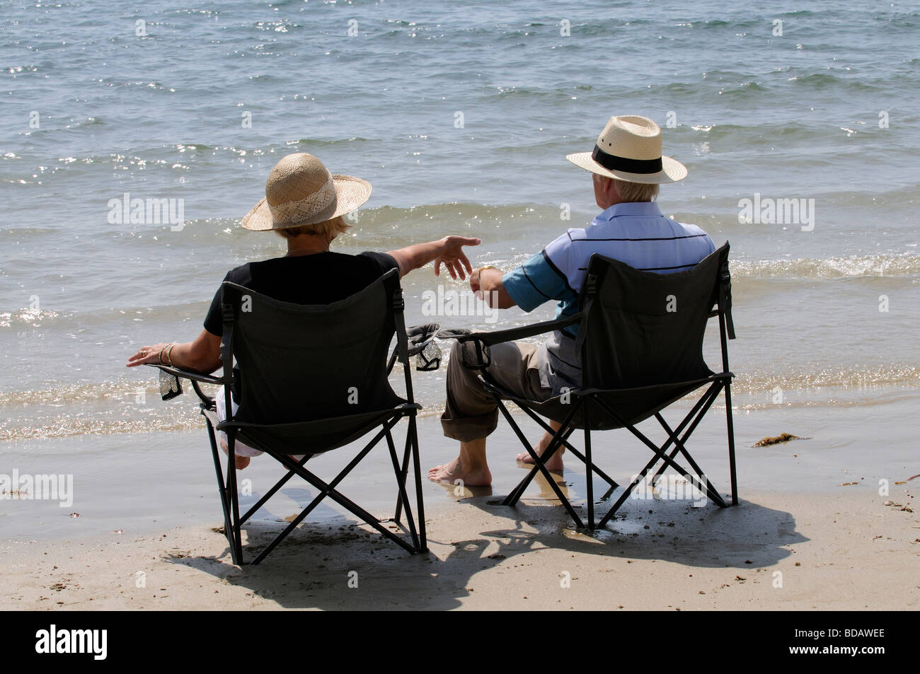 Man and woman sitting relaxing at the seaside retired couple enjoying ...
