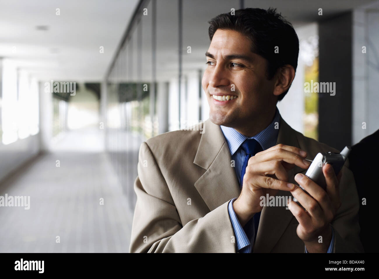 Businessman text messaging on a palmtop and smiling Stock Photo - Alamy
