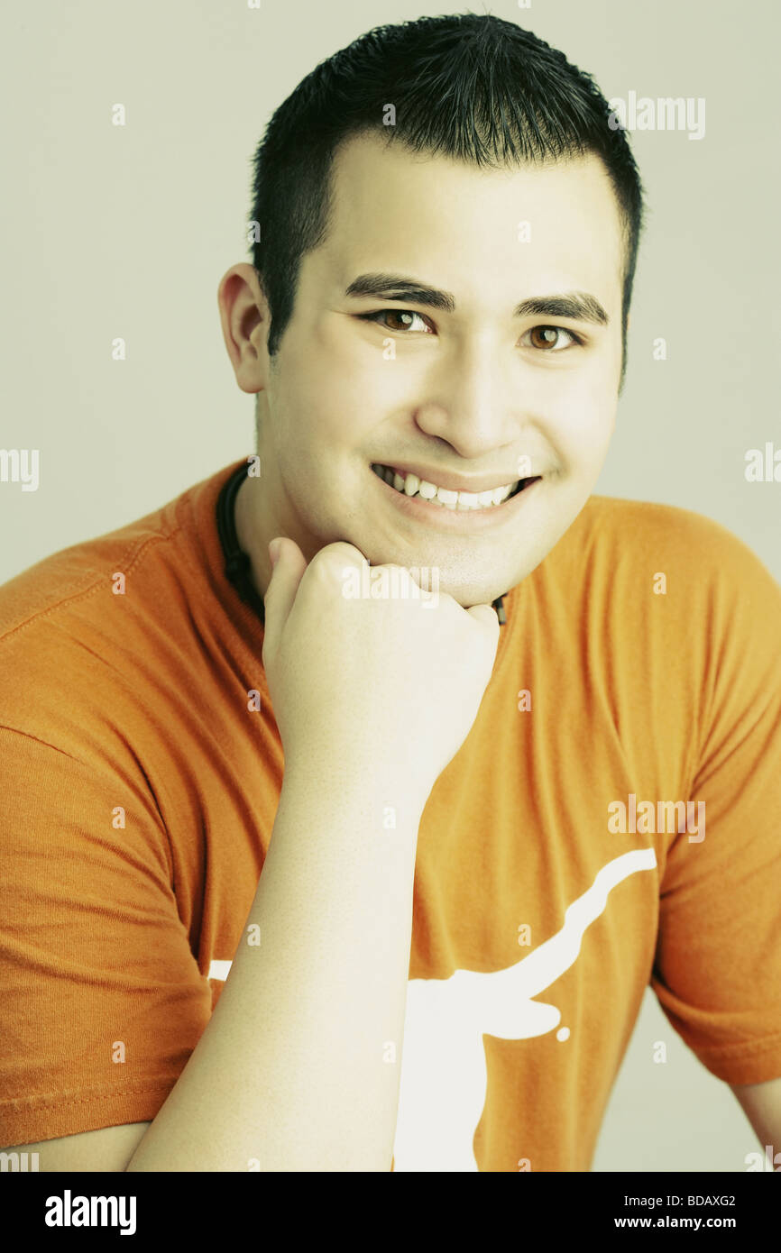 Portrait of a young man smiling with his hand on his chin Stock Photo ...