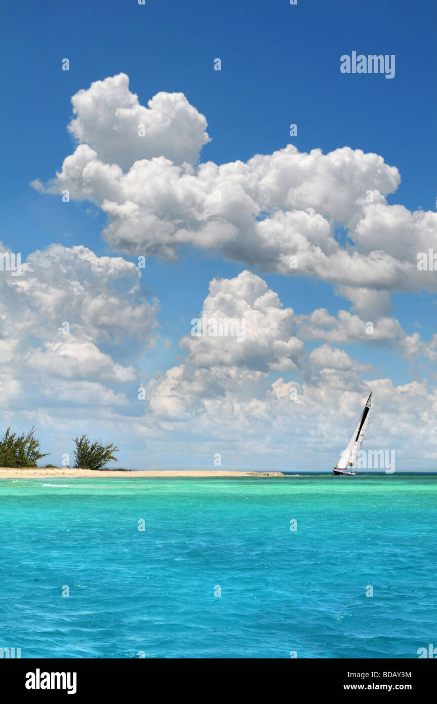 Sailboat sailing clear waters by tropical island Stock Photo - Alamy