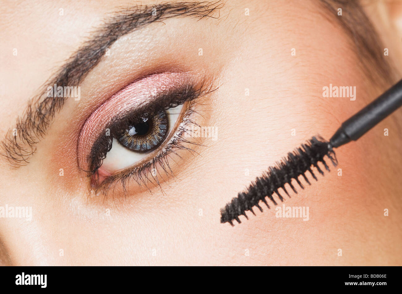 Portrait of a young woman applying mascara on her face Stock Photo - Alamy