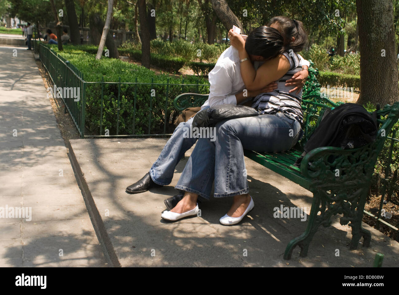 Couple seated on a park bench kissing Stock Photo - Alamy