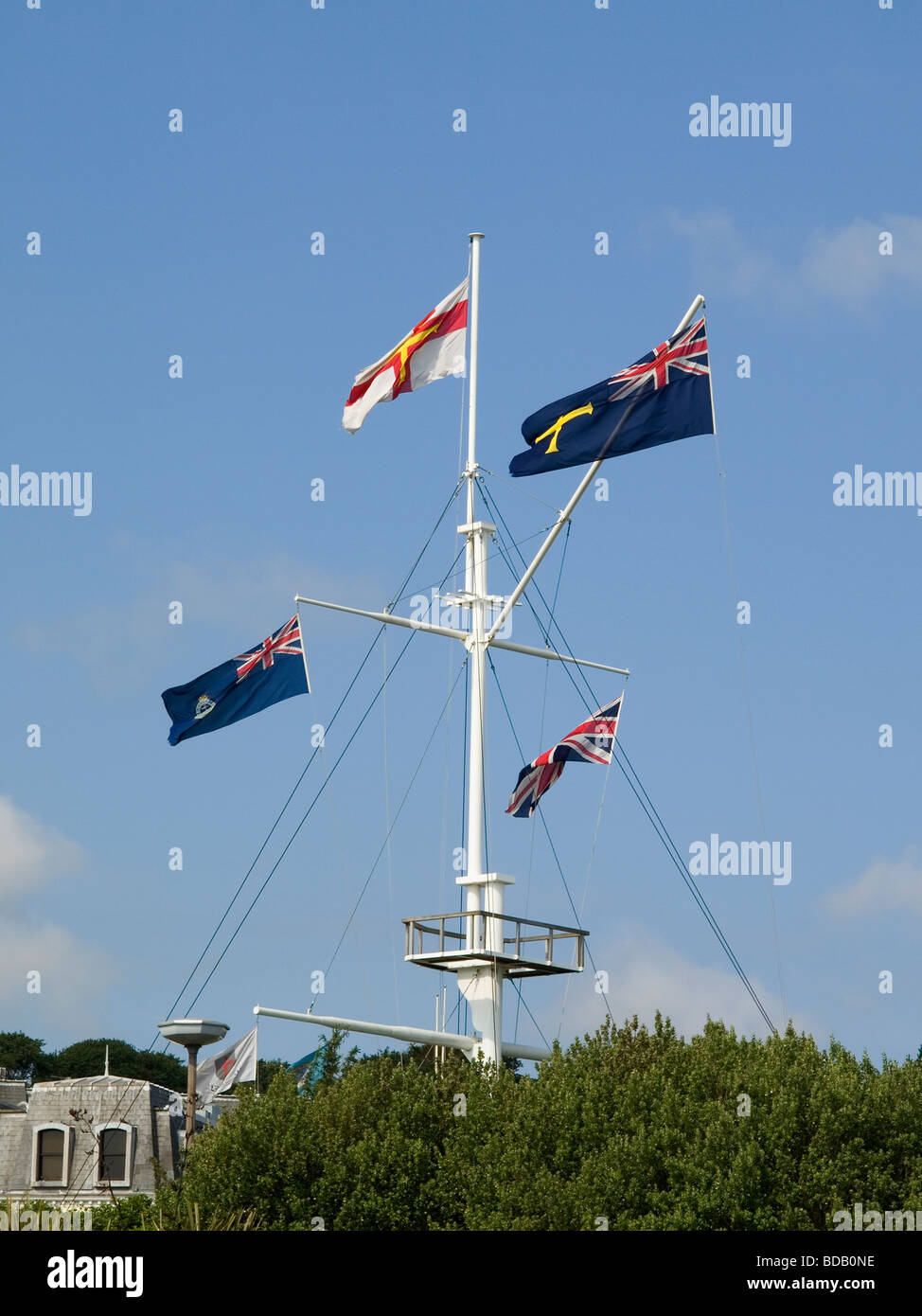 Flags flying on a mast at the road entrance to St Peter Port harbour ...