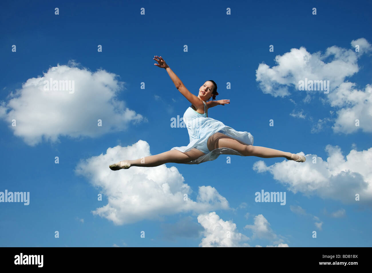 Ballerina performing a jump with clouds in the background Stock Photo ...