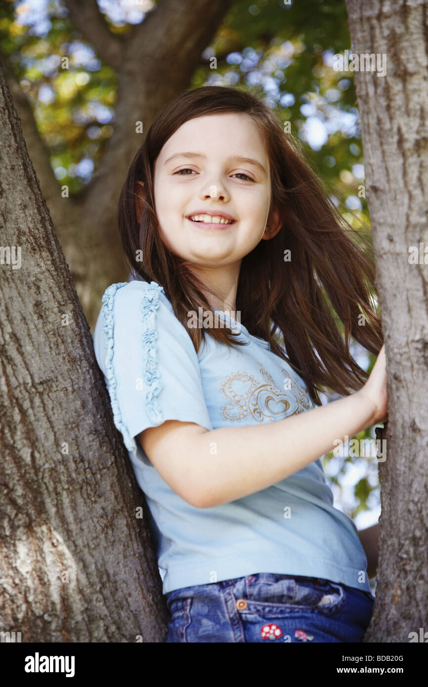 Portrait of a girl sitting on a tree trunk and smiling Stock Photo - Alamy