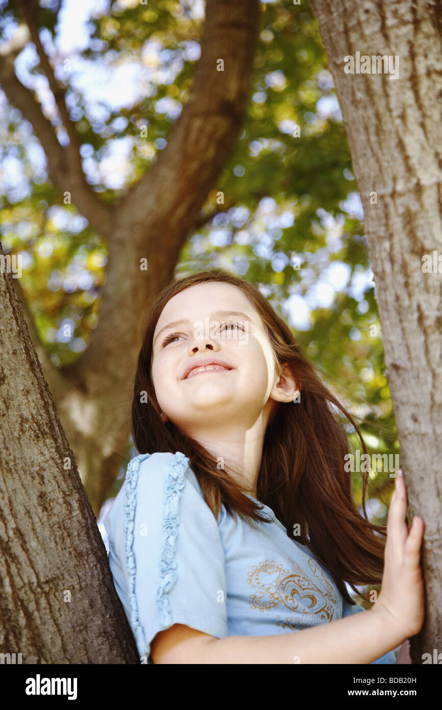 Low angle view of a girl near a tree trunk and smiling Stock Photo - Alamy